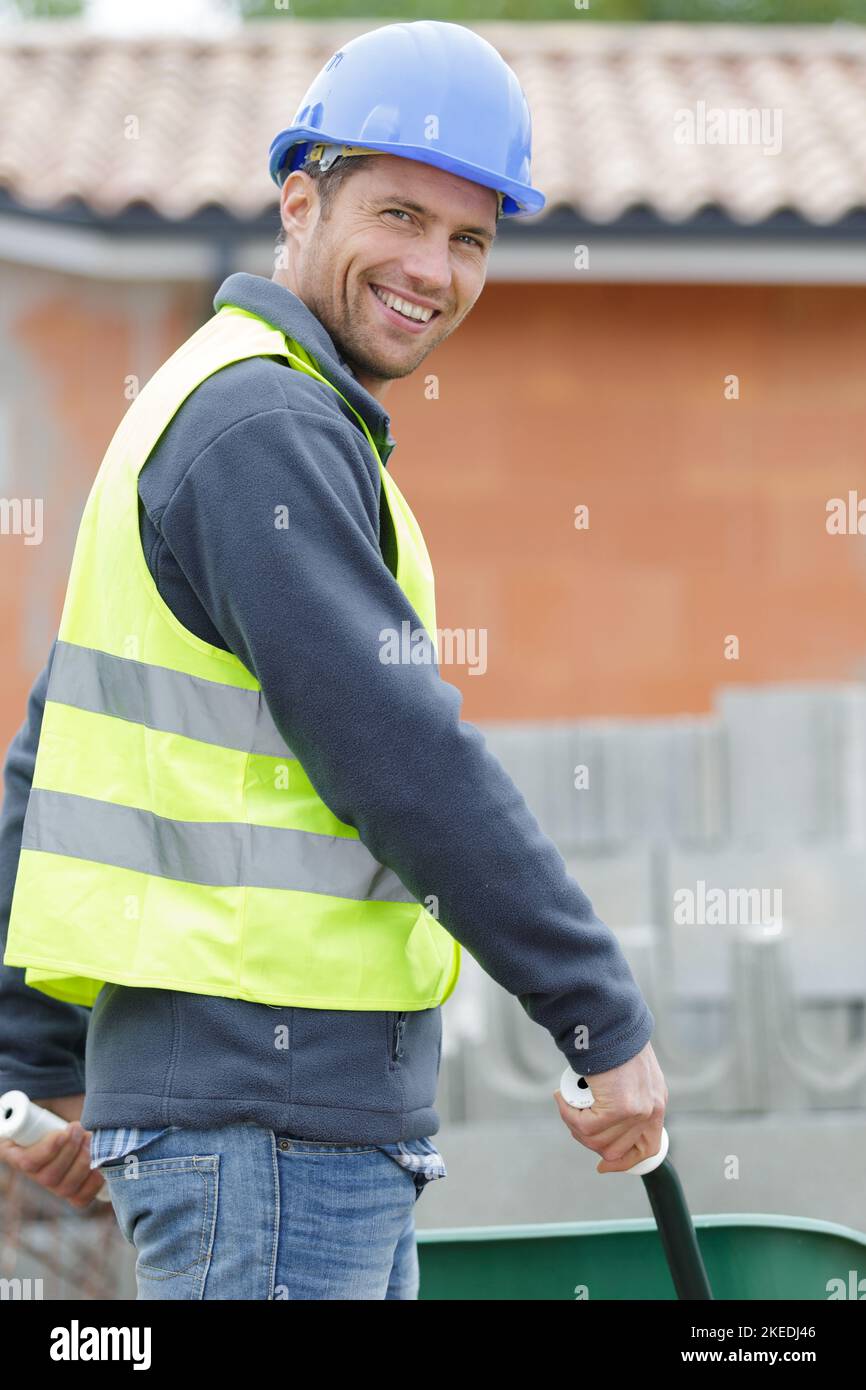 happy construction worker pushing a wheelbarrow Stock Photo - Alamy