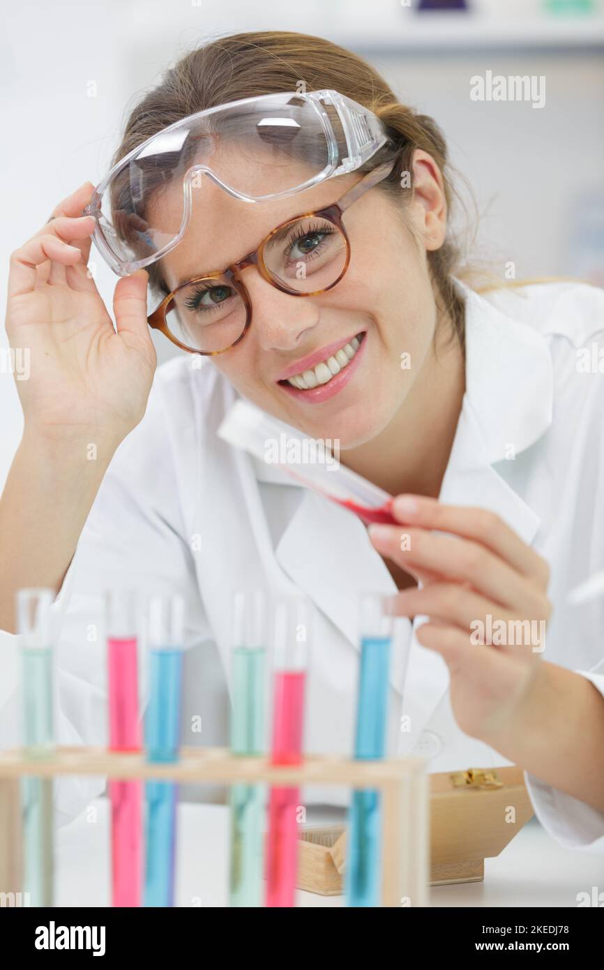 smiling chemist wearing safety glasses and coat sitting in lab Stock ...
