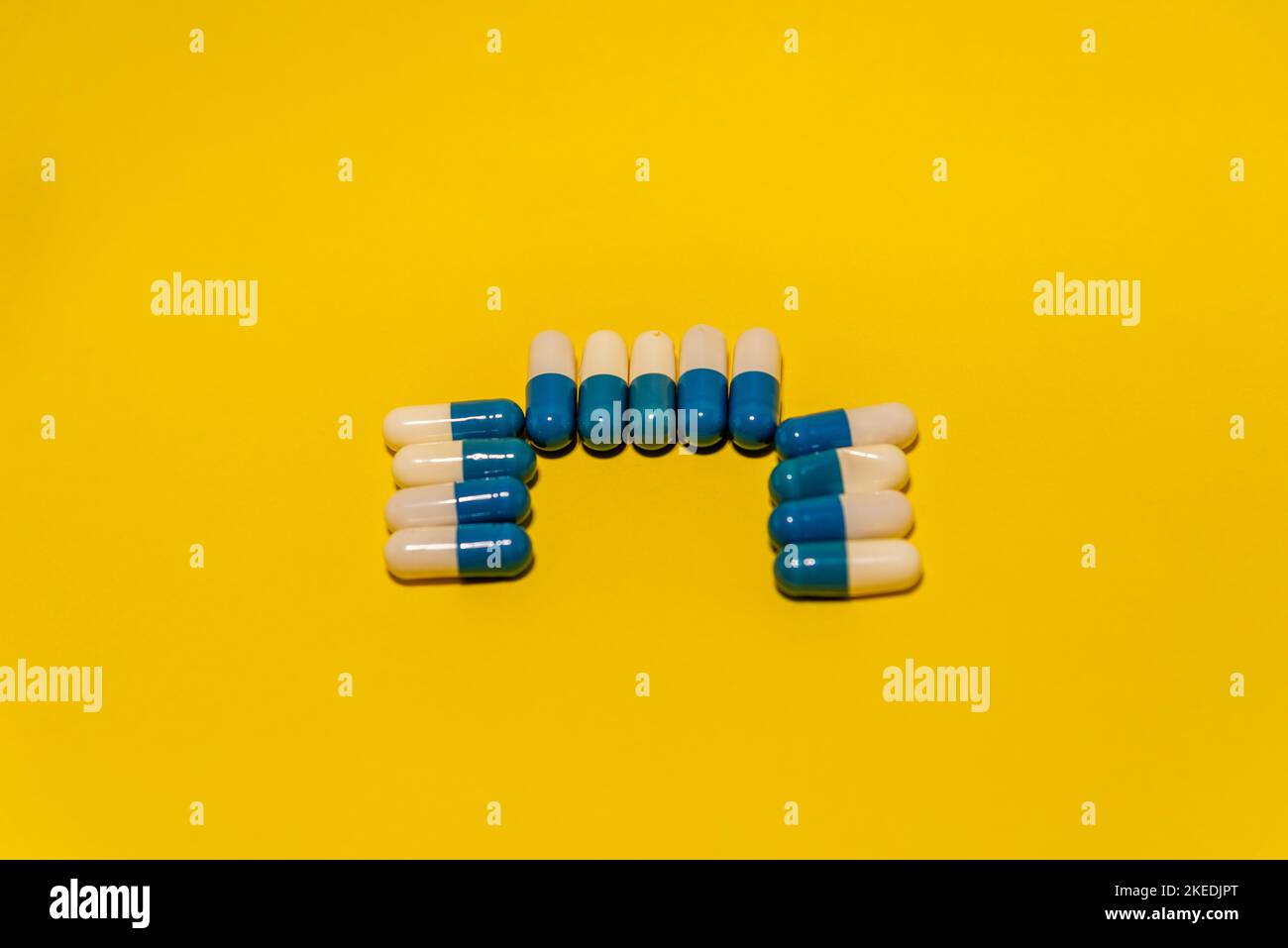 A bunch of blue white medical capsules isolated on a yellow background ...