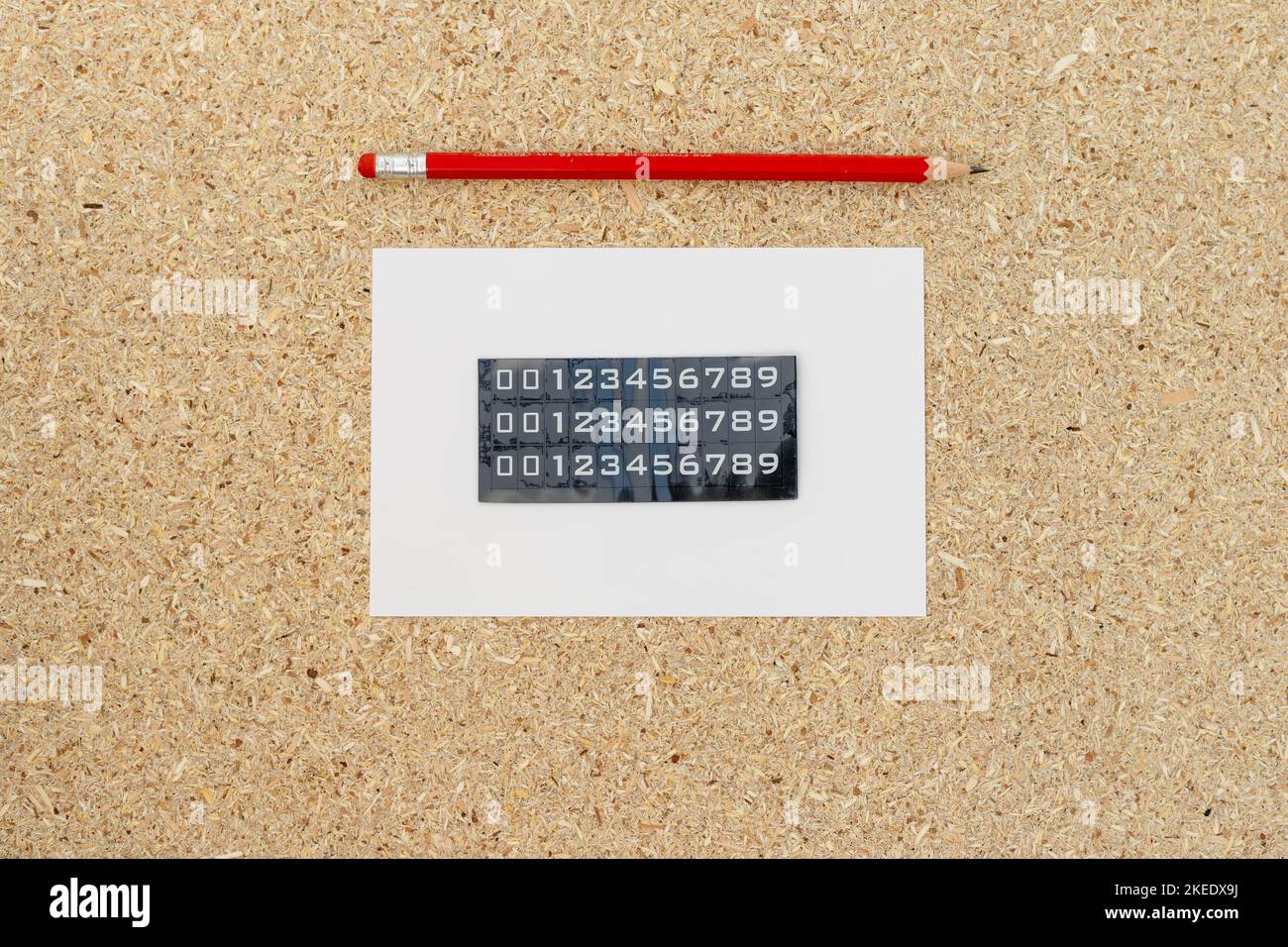 Sticker numbers on white post card with pencil on a cork board ...