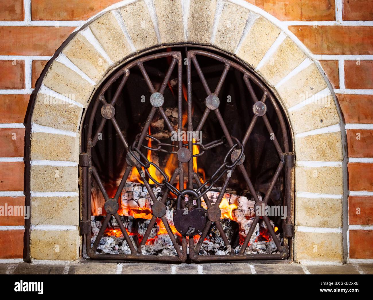 Burning firewood in a fireplace closed to a chain with a padlock Stock ...