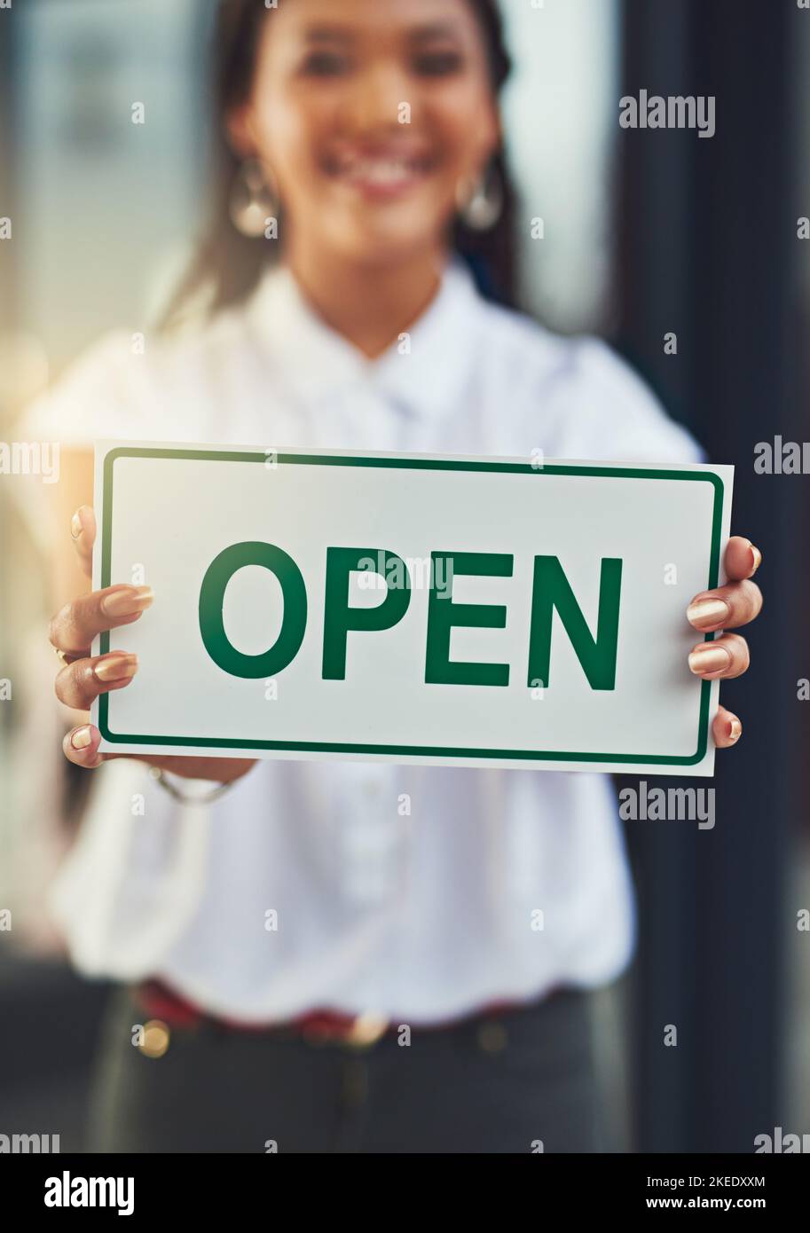 Open and ready for business. Portrait of a young business owner holding ...