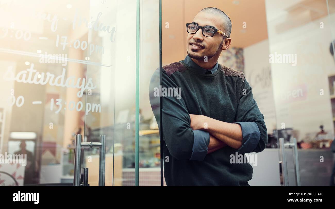 Waiting for his first customer. a young man standing in the entrance of ...
