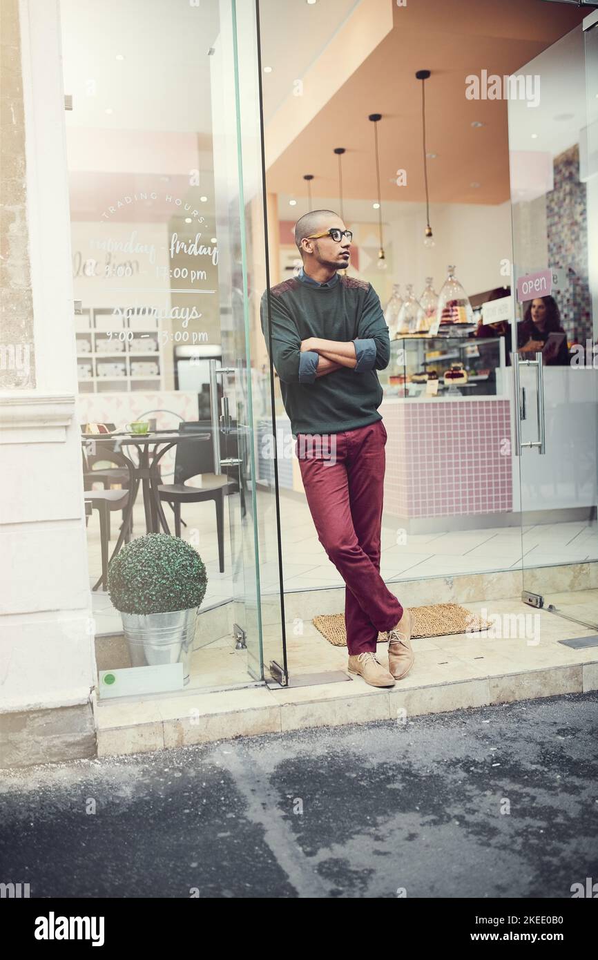 Ready to welcome his first customers. a young man standing in the ...