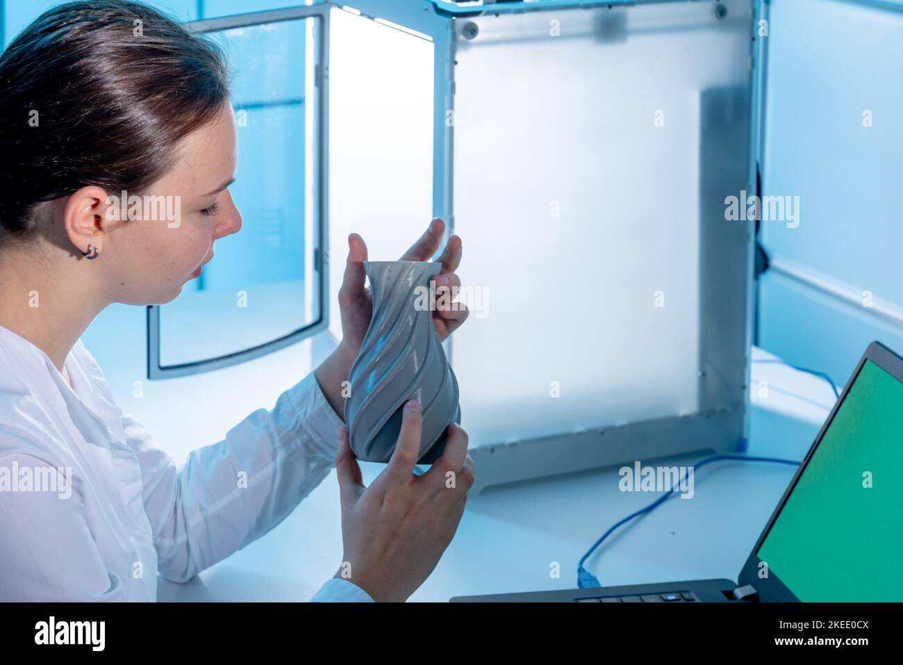 young woman in a 3D printing science laboratory examines a model ...