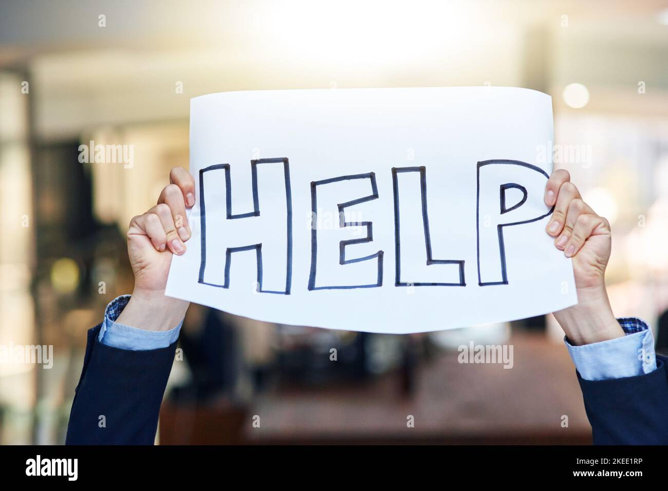 Lend a helping hand. a businessman holding up a sign asking for help ...