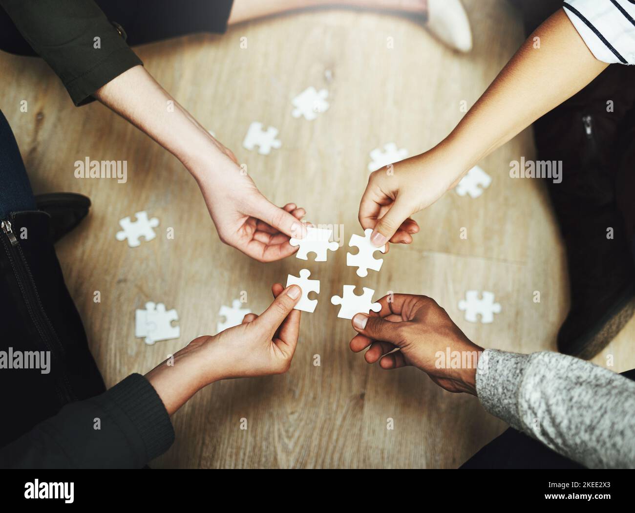 Putting all the pieces together. a group of unrecognizable people fitting puzzle pieces together ...