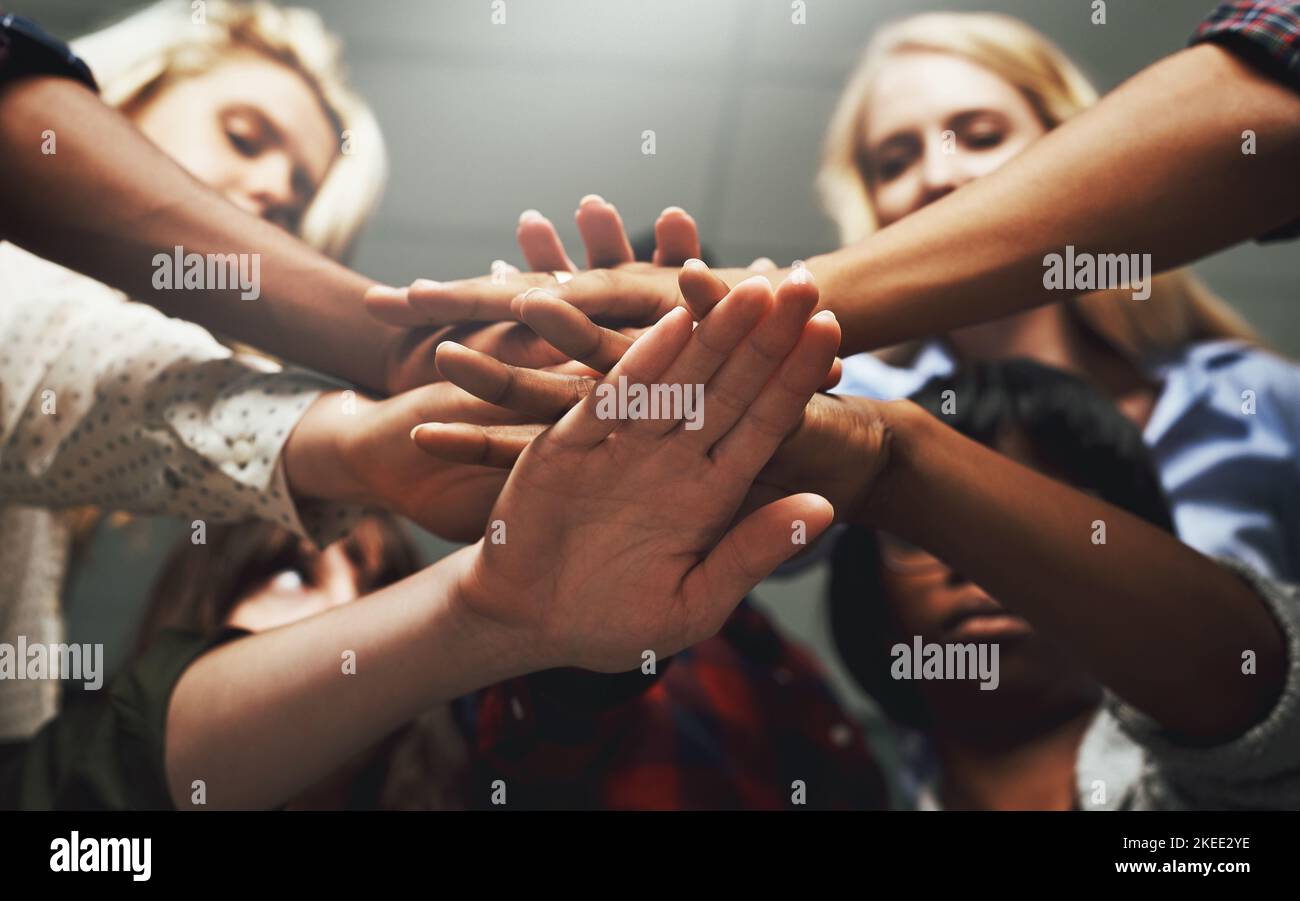 All together now. a group of cheerful work colleagues forming a huddle ...