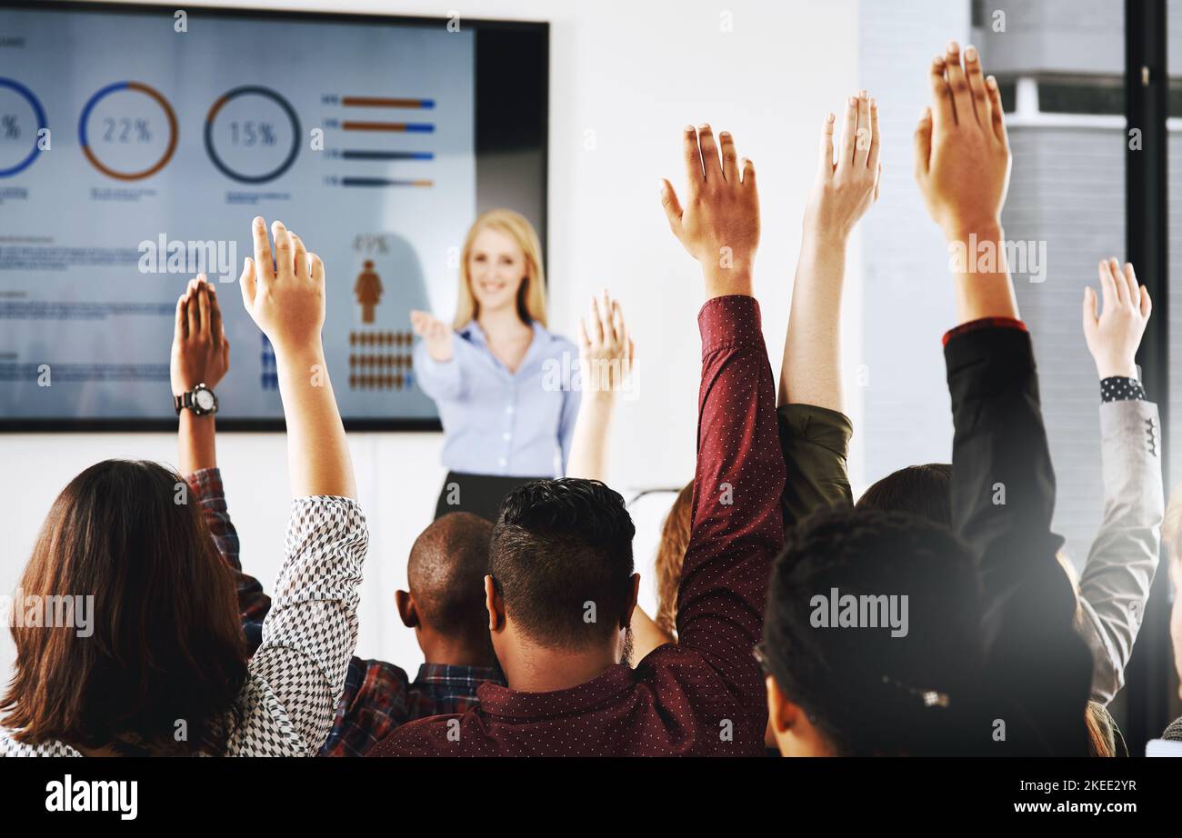 Ask away. a group of unrecognizable businesspeople raising their hands to ask questions during a ...