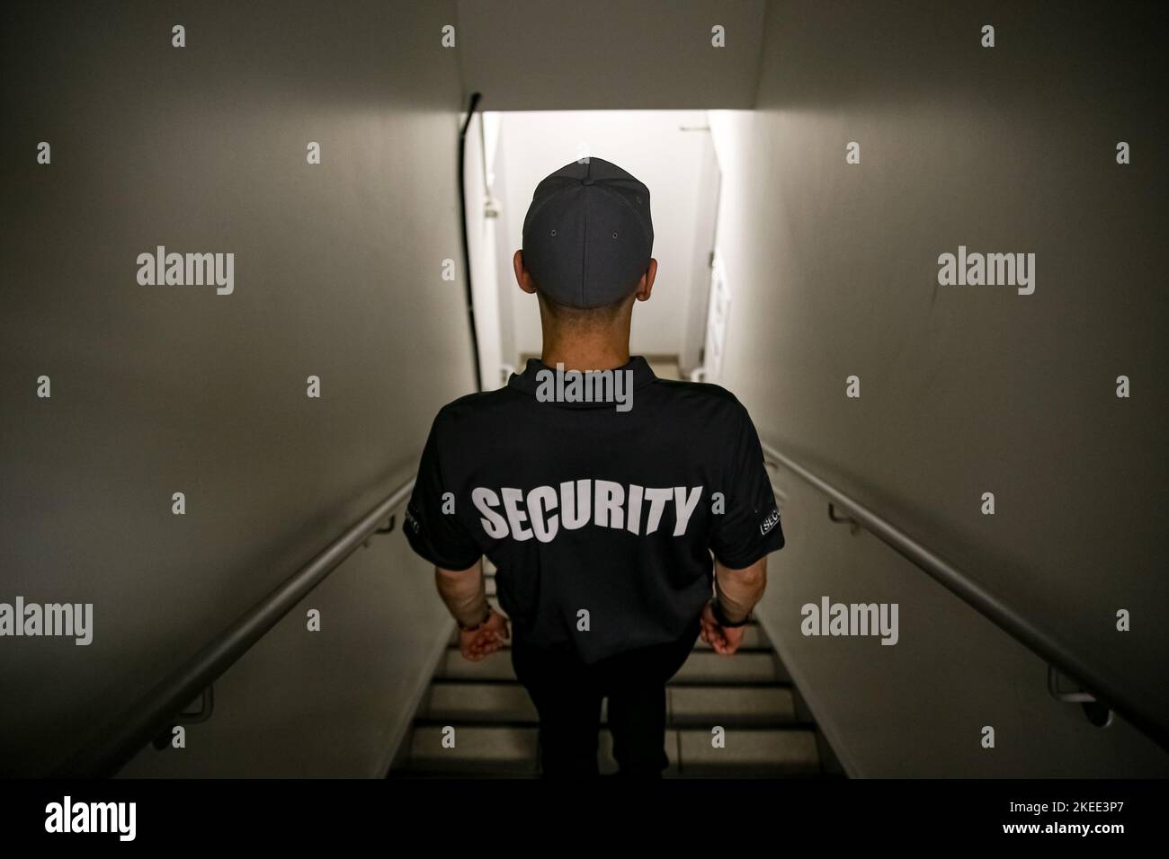 A security guy with a black hat and a uniform walking down the stairs ...