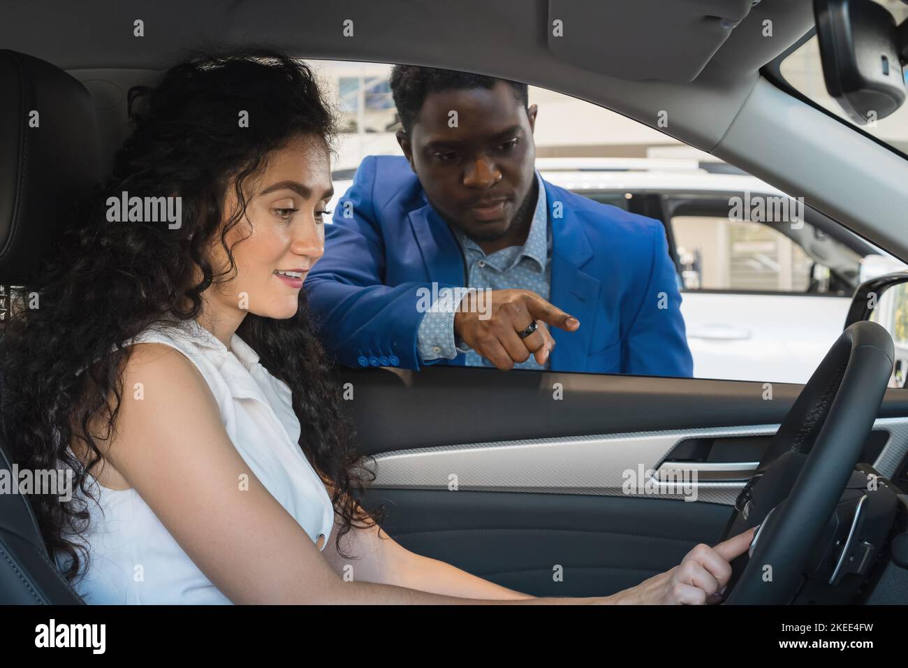 Black-haired lady driver and dealer examine car in showroom Stock Photo ...