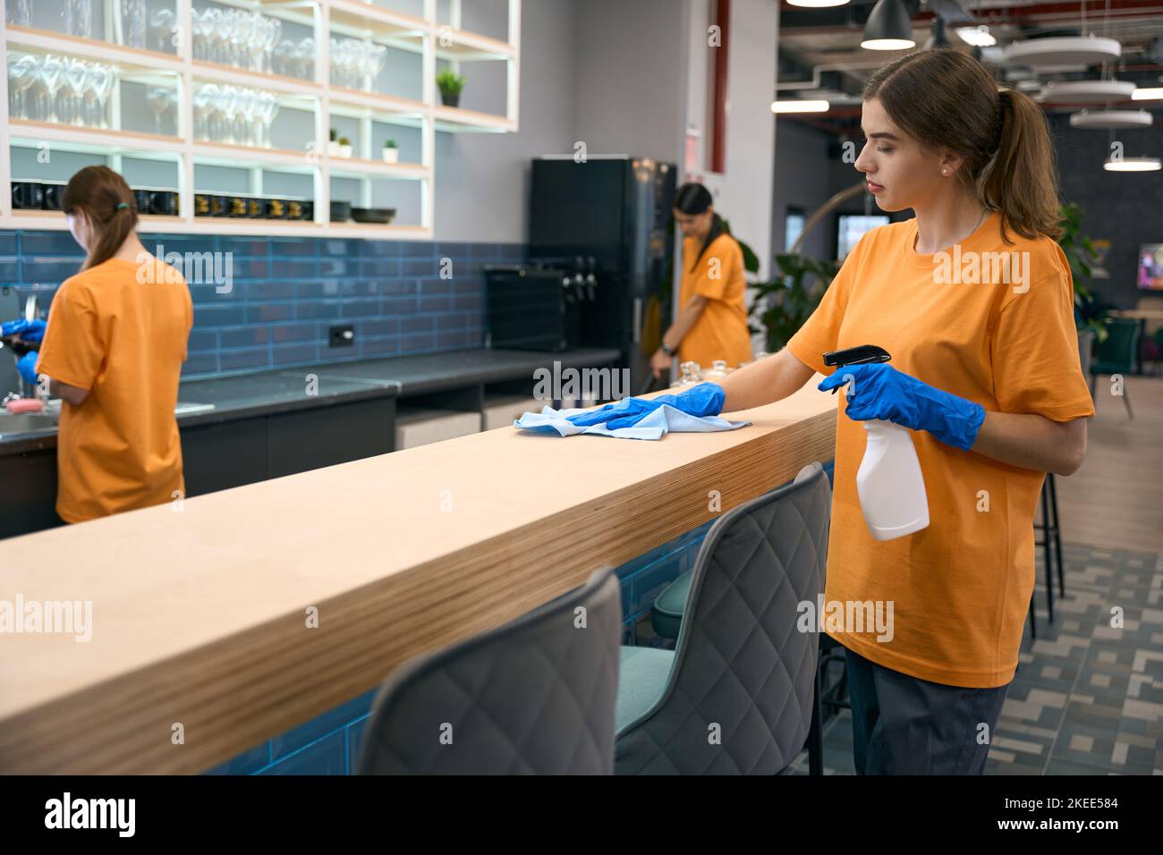 Cleaning female team washes and disinfects surfaces in the kitchen area ...