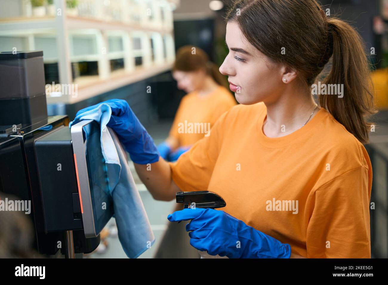 Employee cleaning company washes coffee machine in a coworking area ...