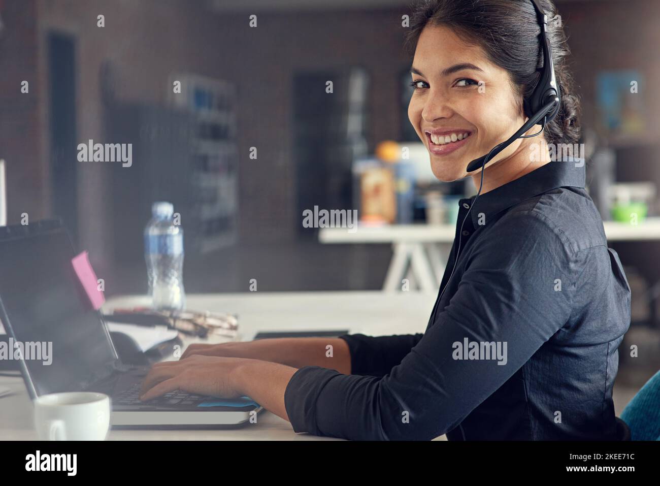 Shes above and beyond the call. a call centre agent sitting at her desk ...