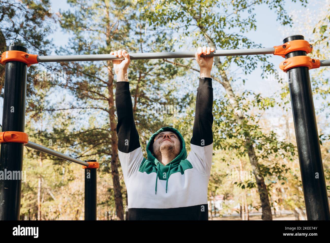 Young caucasian unshaven man 34 years old doing pull ups at the gym ...