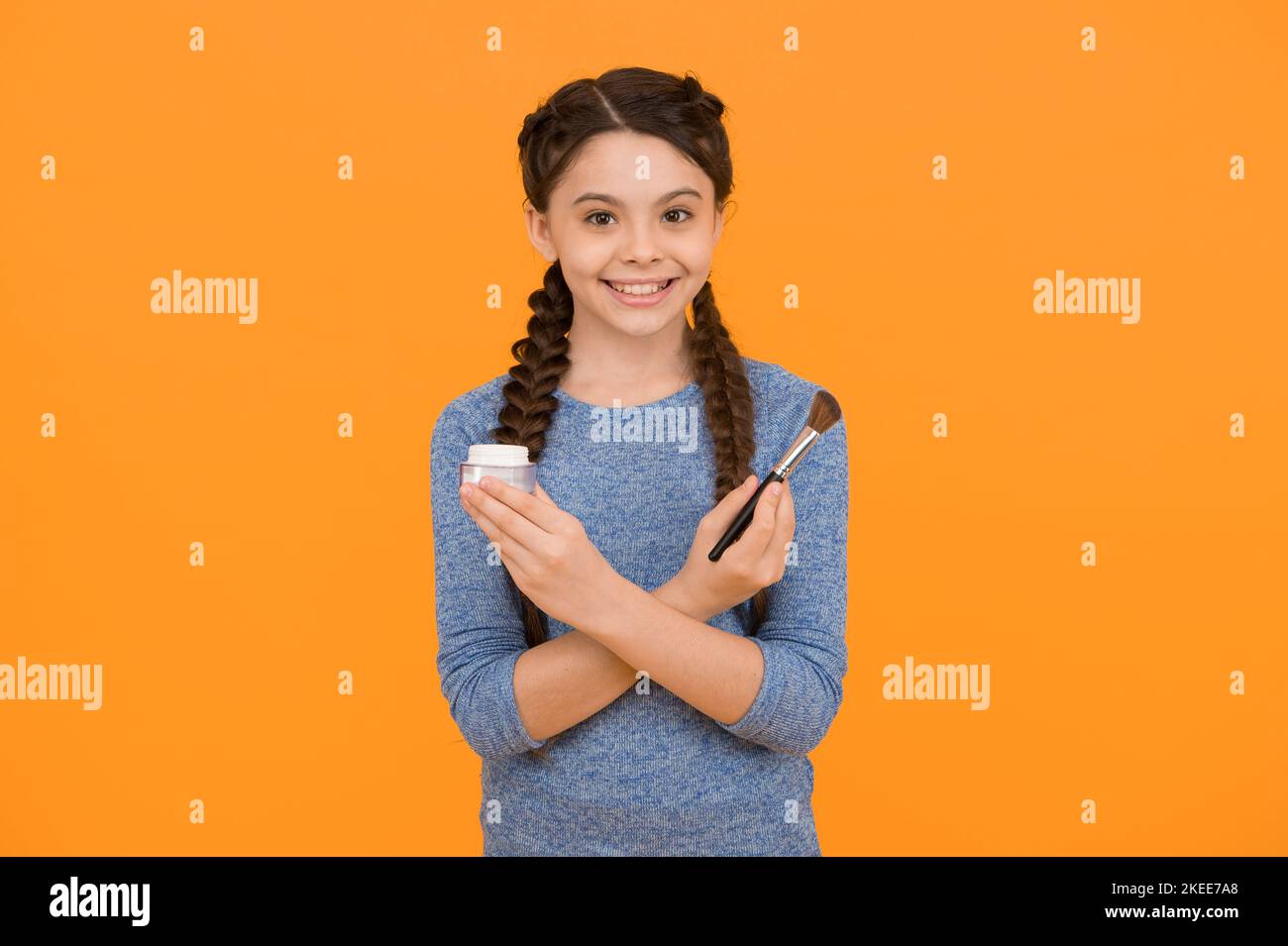 happy teen girl with braided hair use powder and brush on yellow ...