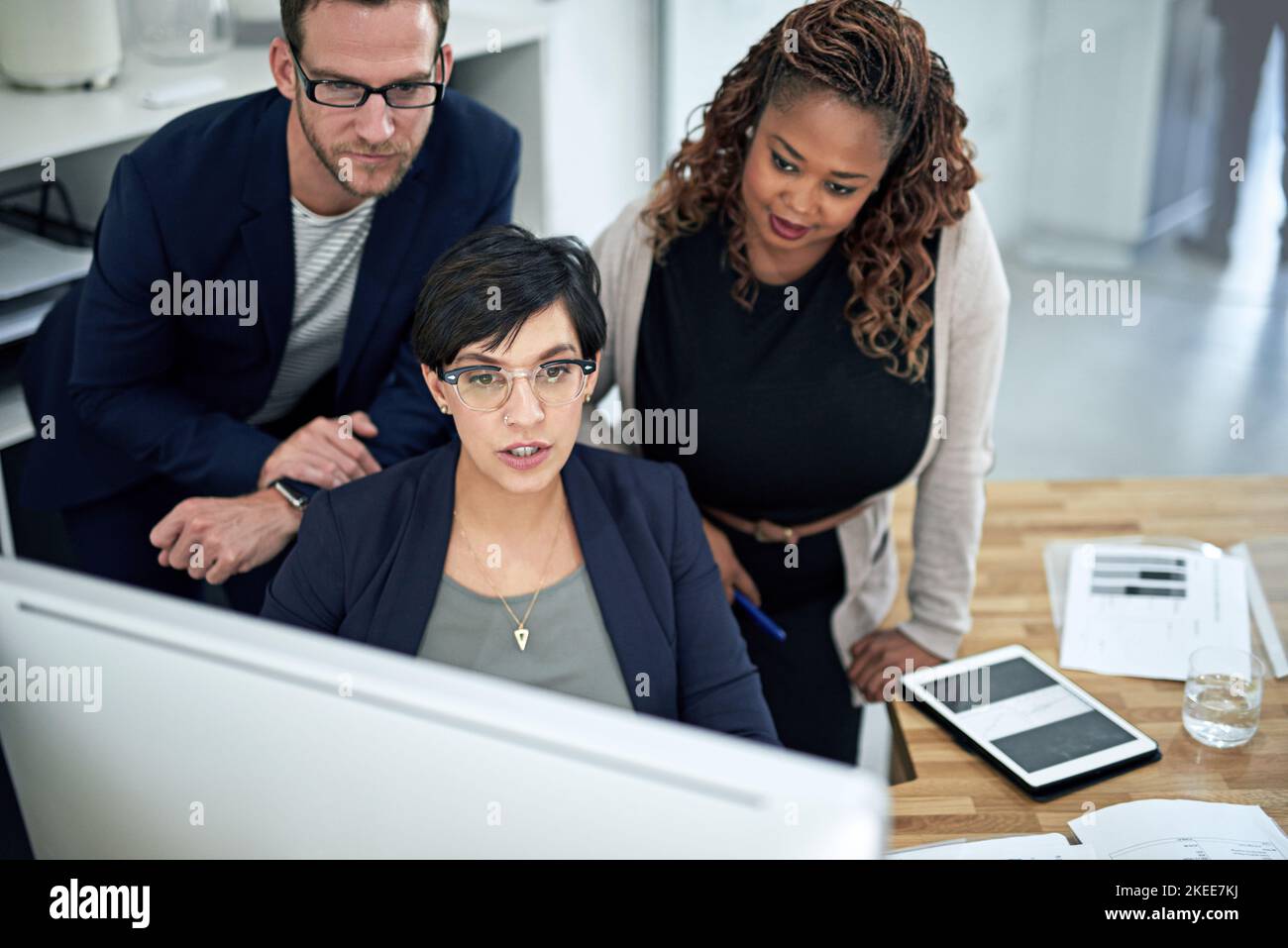 Getting her team involved. three colleagues working in the office Stock ...