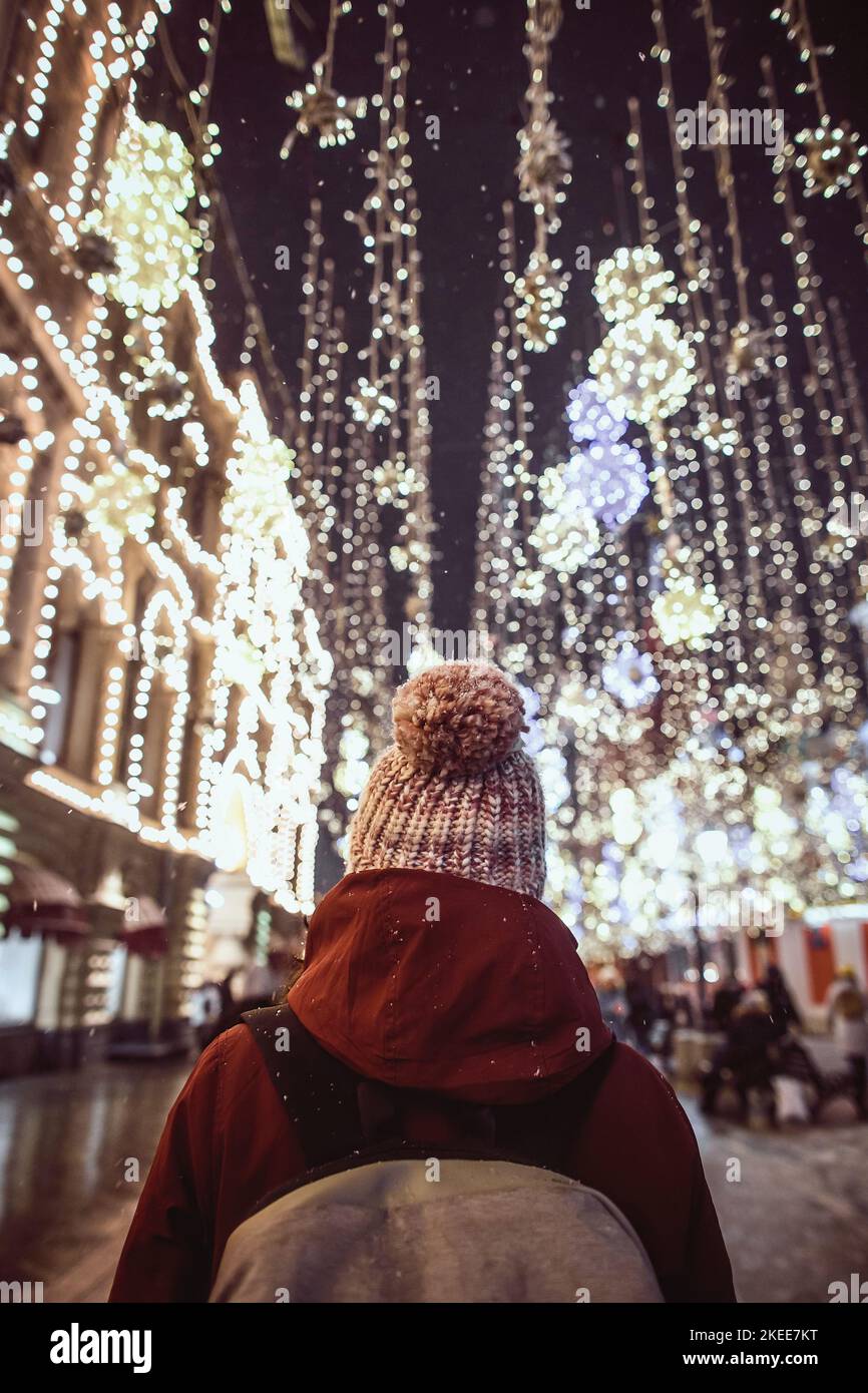 Rear view of a winter hat in a winter hat walks down the street with ...