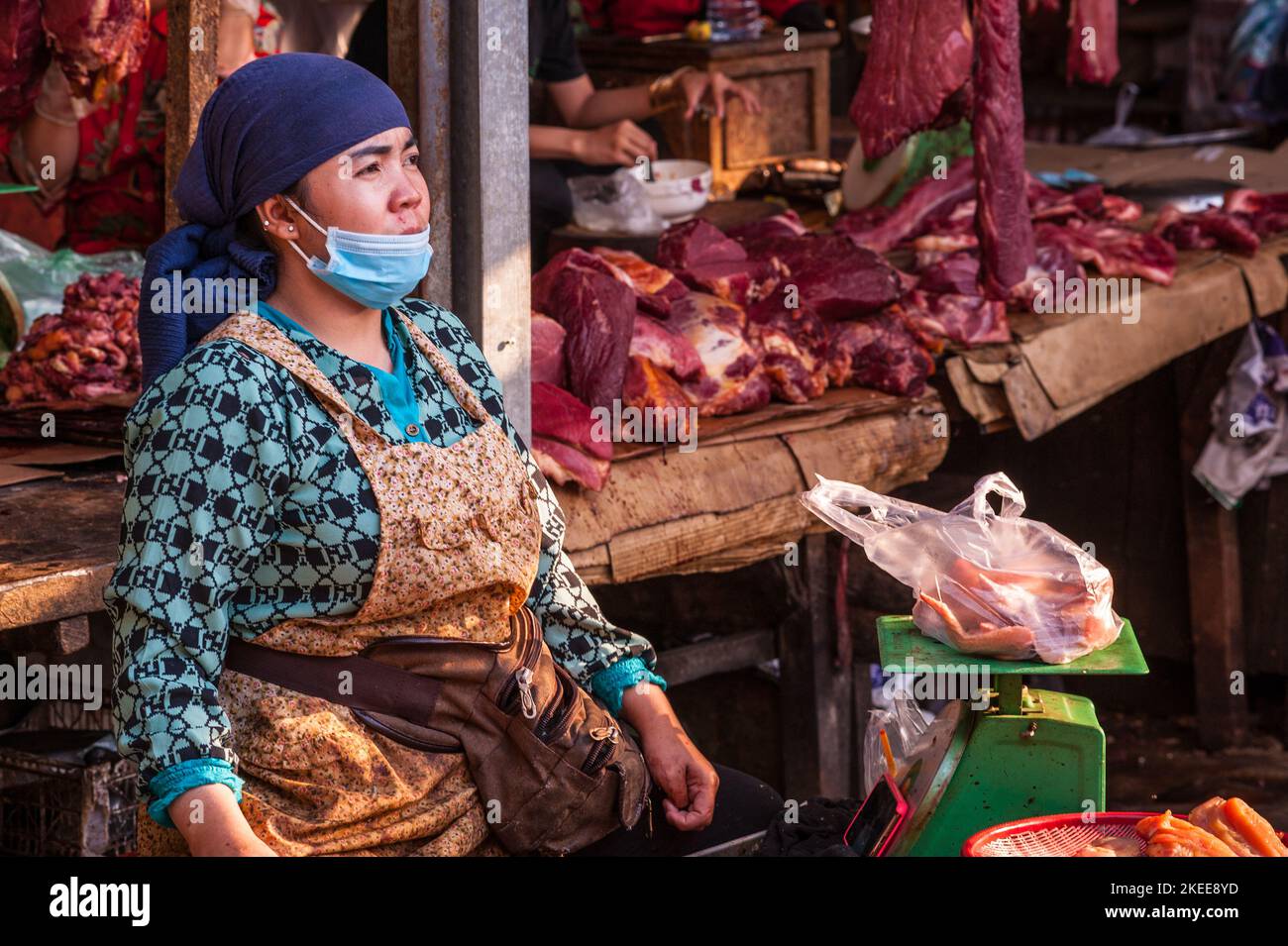 A Cambodian raw meat vendor wearing a face mask & using a weighing ...