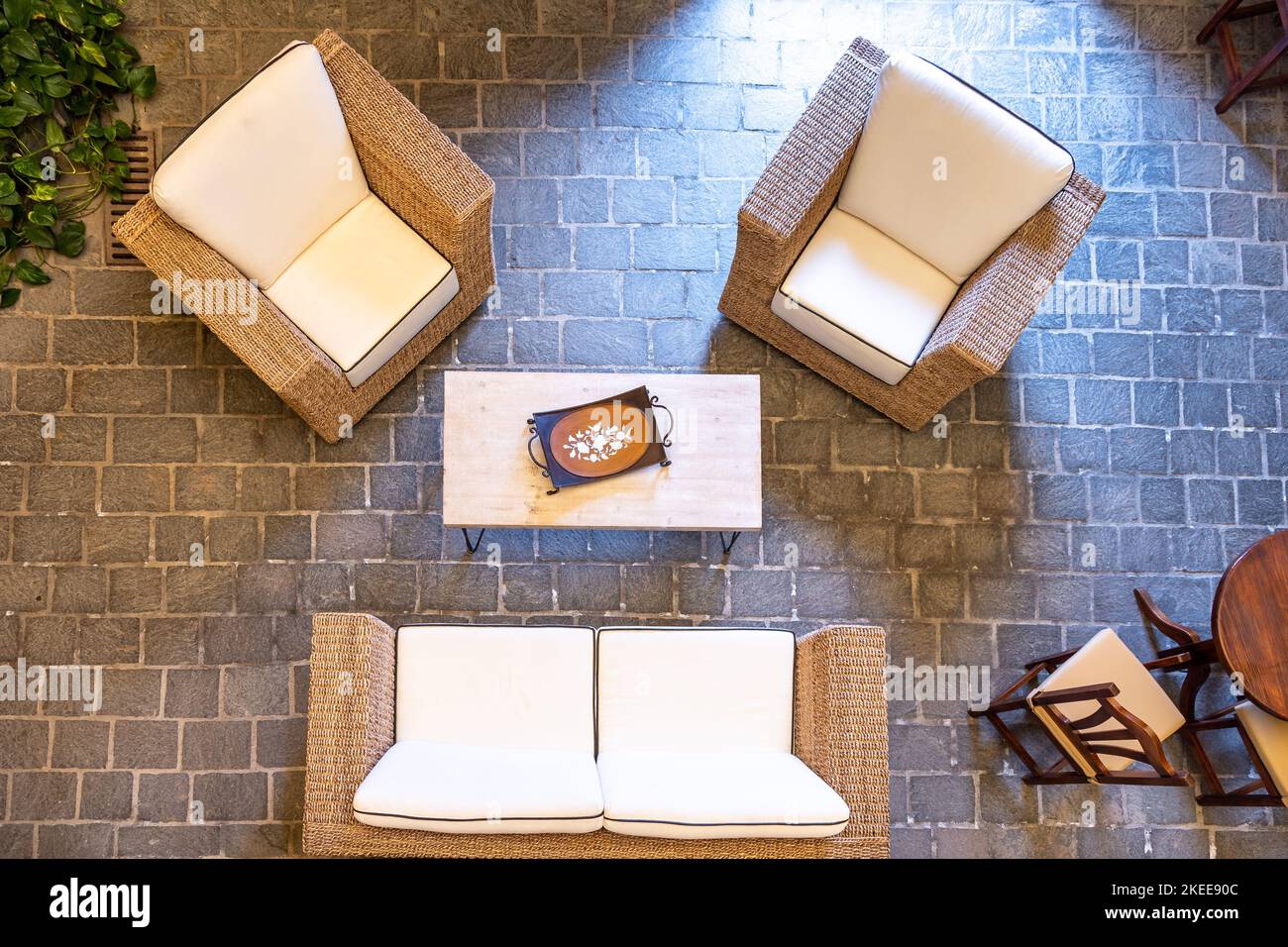 A high-angle top shot of white and beige straw sofa and table, paving ...