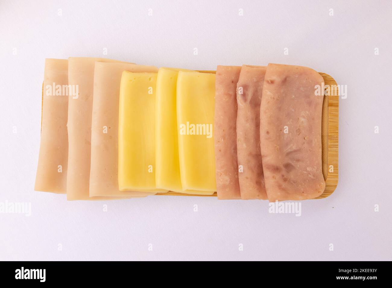 A top closeup of slices of ham and cheese on the wooden narrow and long ...
