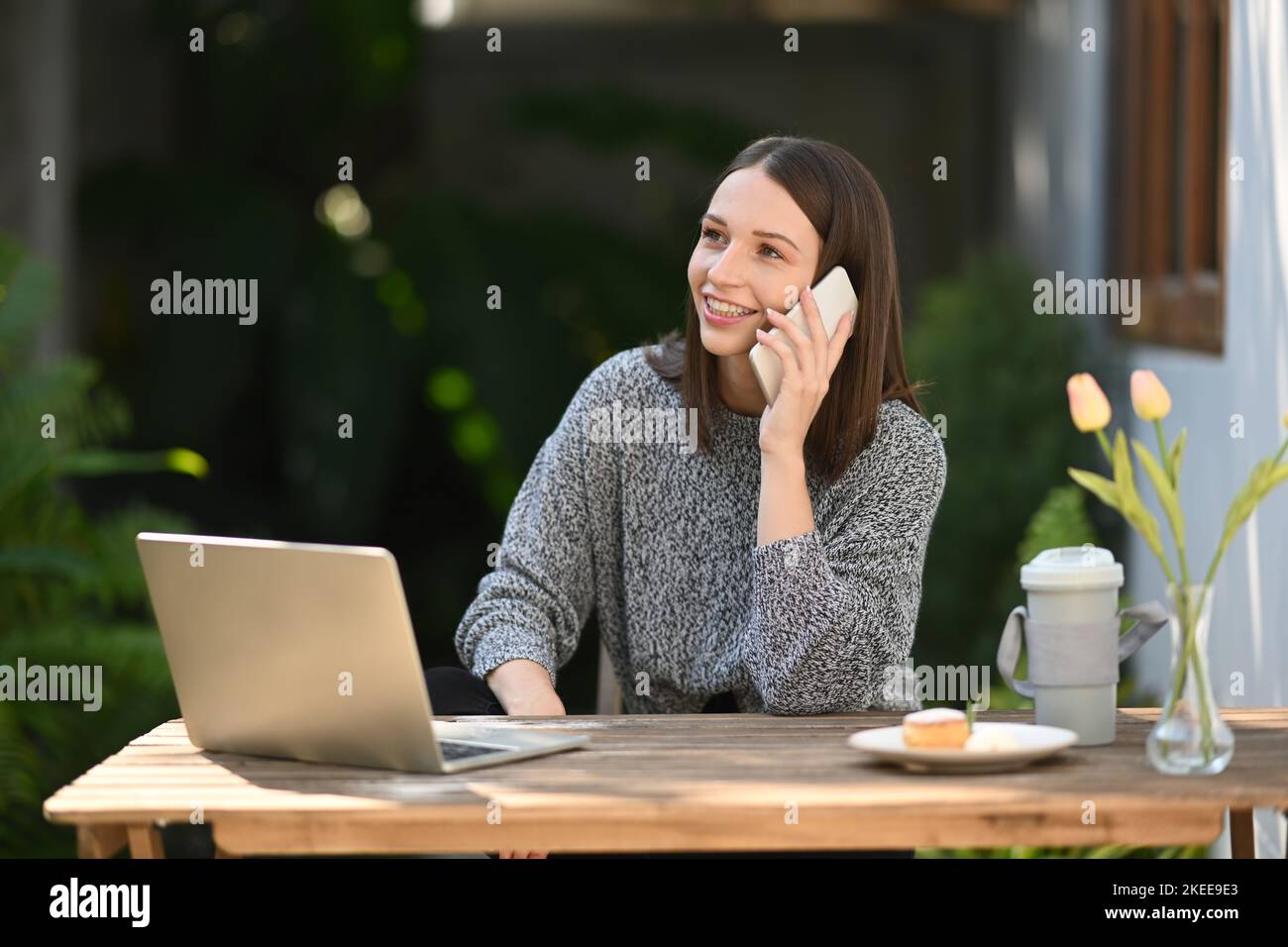 Gorgeous millennial woman having pleasant phone conversation with her ...
