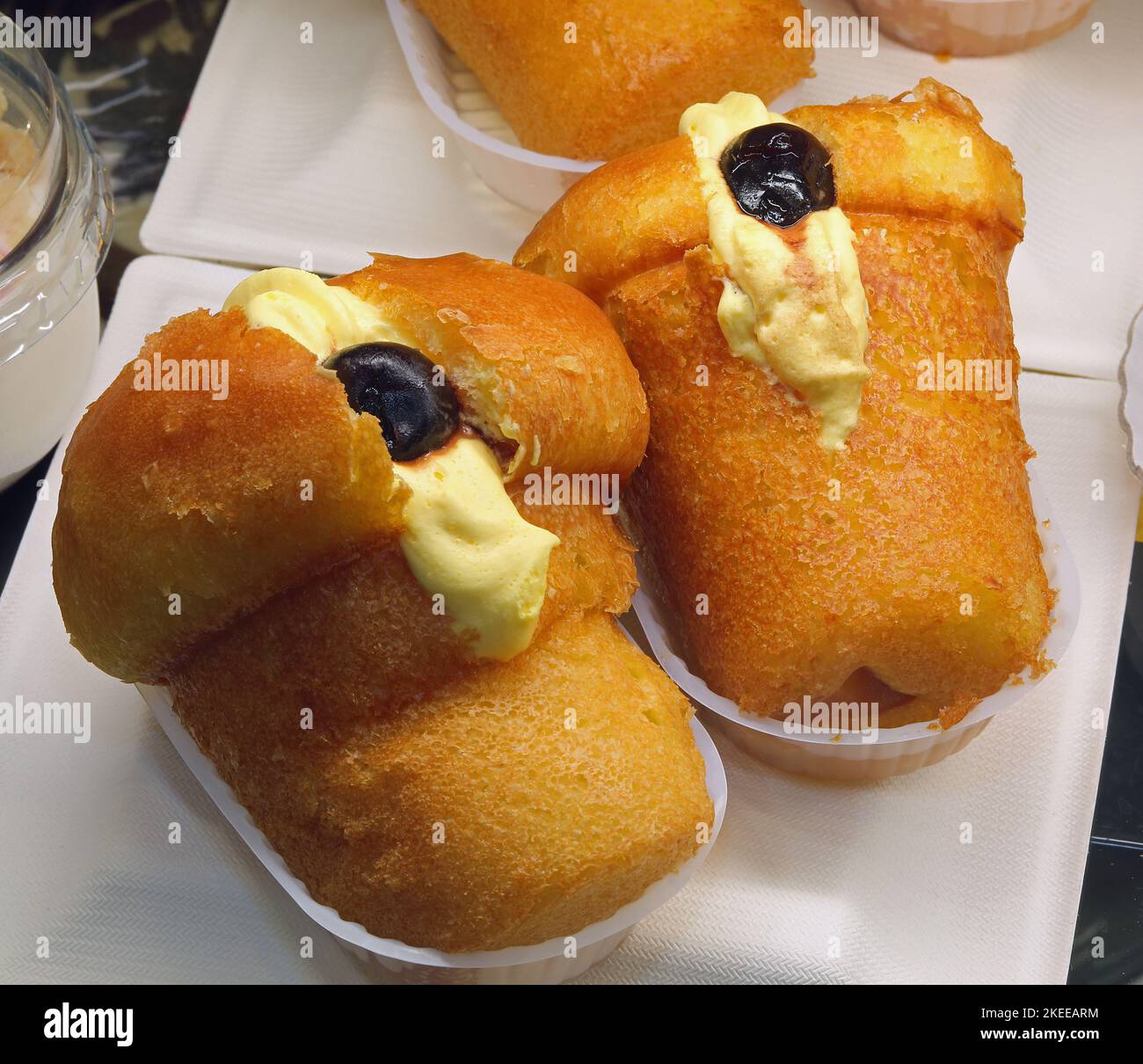 two typical Neapolitan pastries called BABA with custard and alcoholic ...