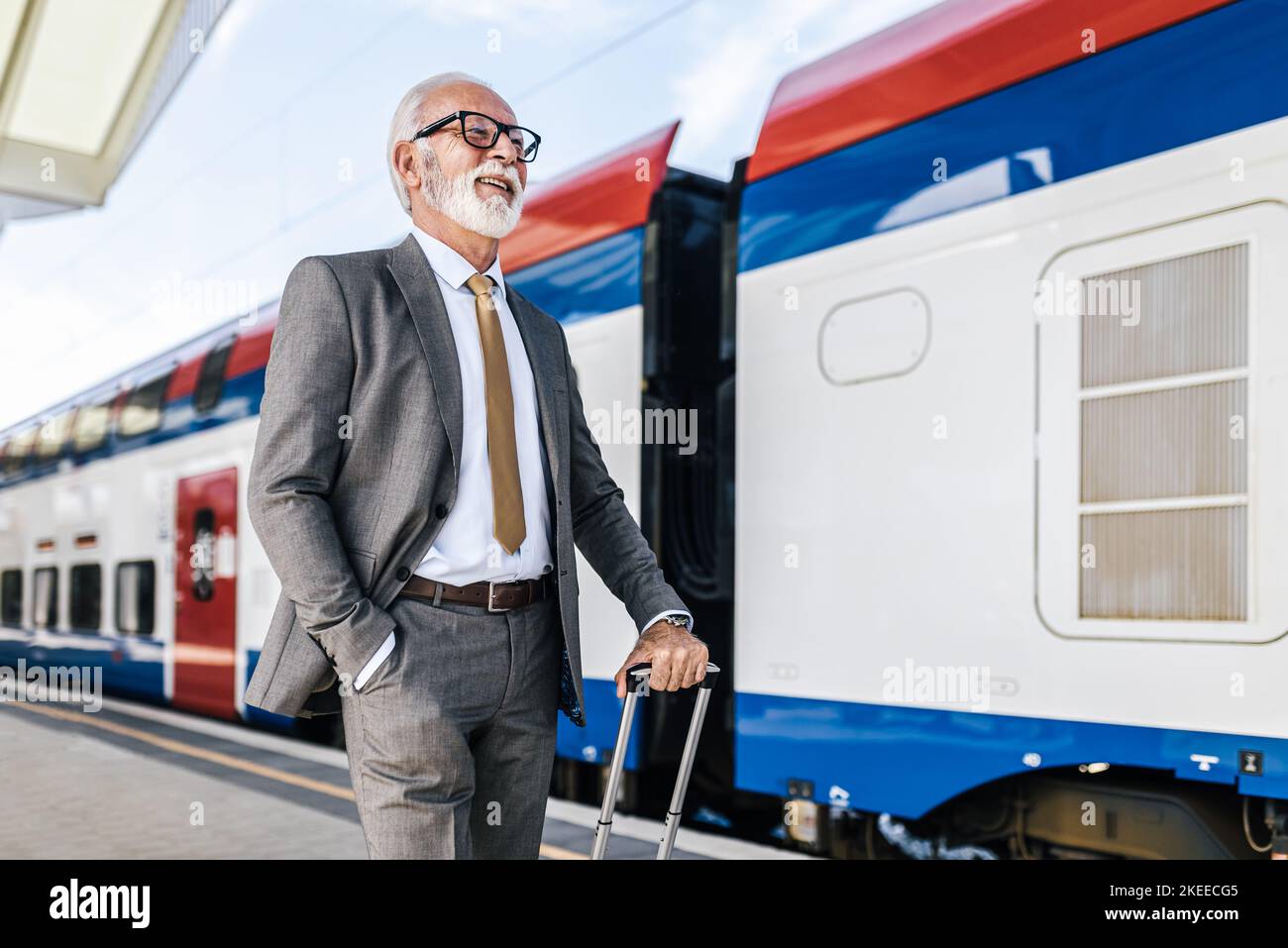 Senior smiling male professional waiting at railroad train station ...