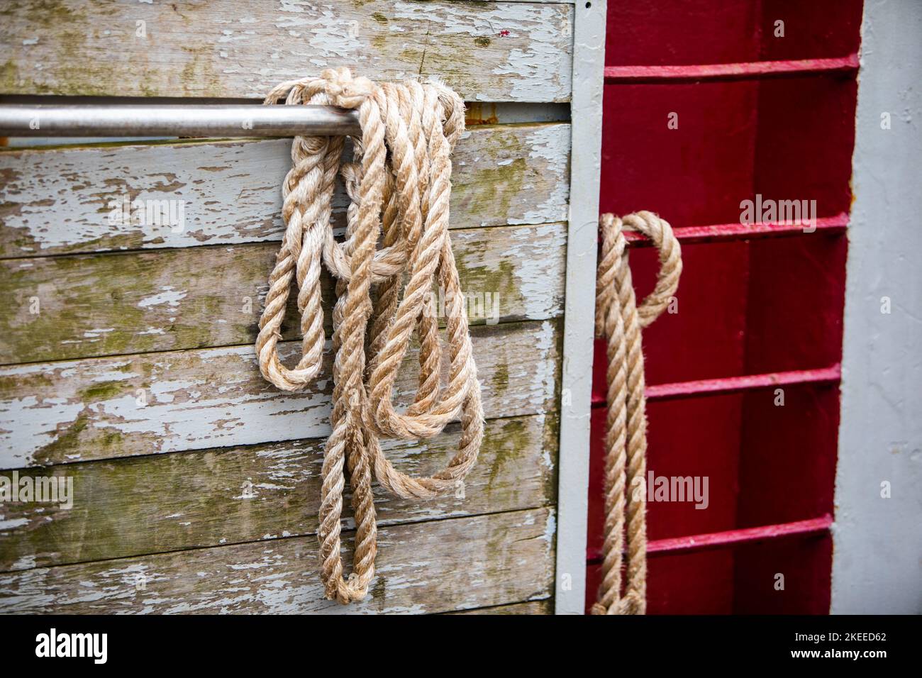 The ropes hanging from a metallic handrail of a wooden wall Stock Photo ...