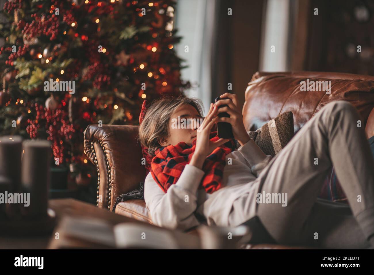 Young teen boy with long hair holding smartphone using wireless technology mobile device for ...