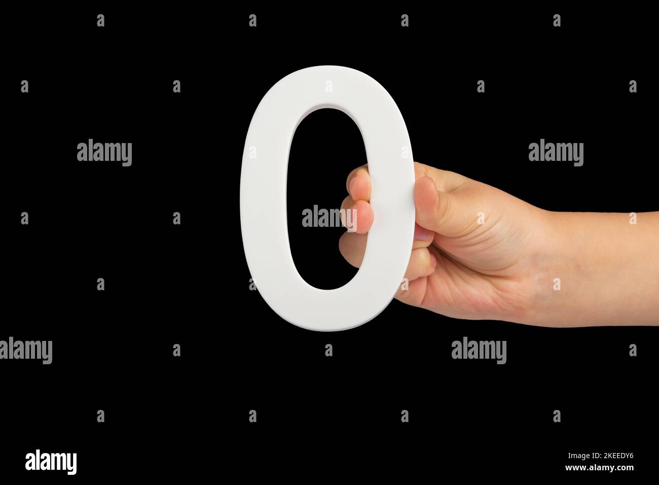 Zero in hand. The number zero is clasped in a hand isolated on a black ...