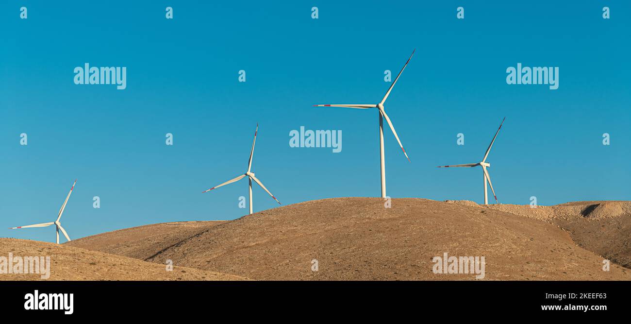 Multiple wind turbines standing on a hill at sunrise and generating ...