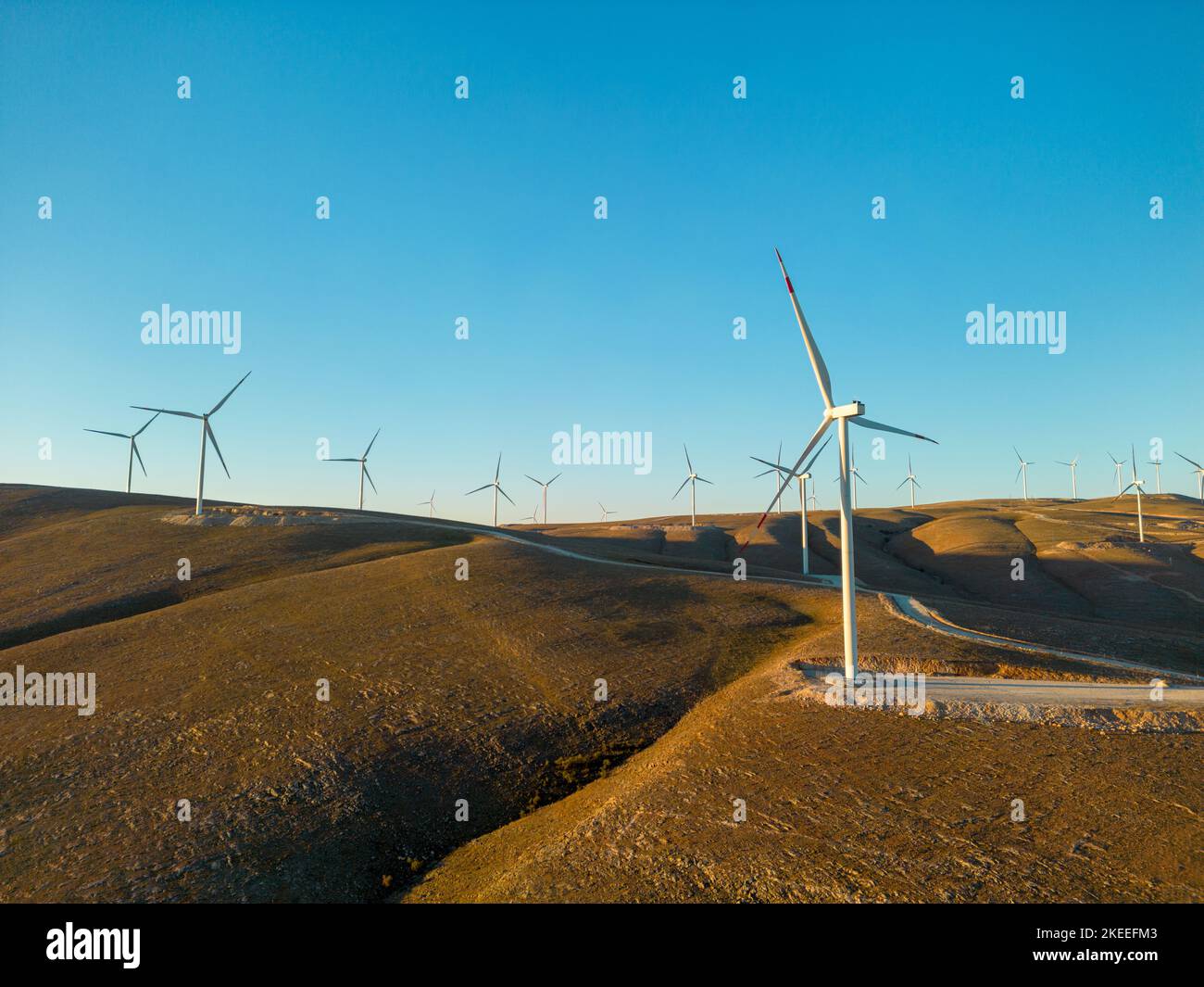 Aerial view of multiple wind turbines standing on a hill and generating ...