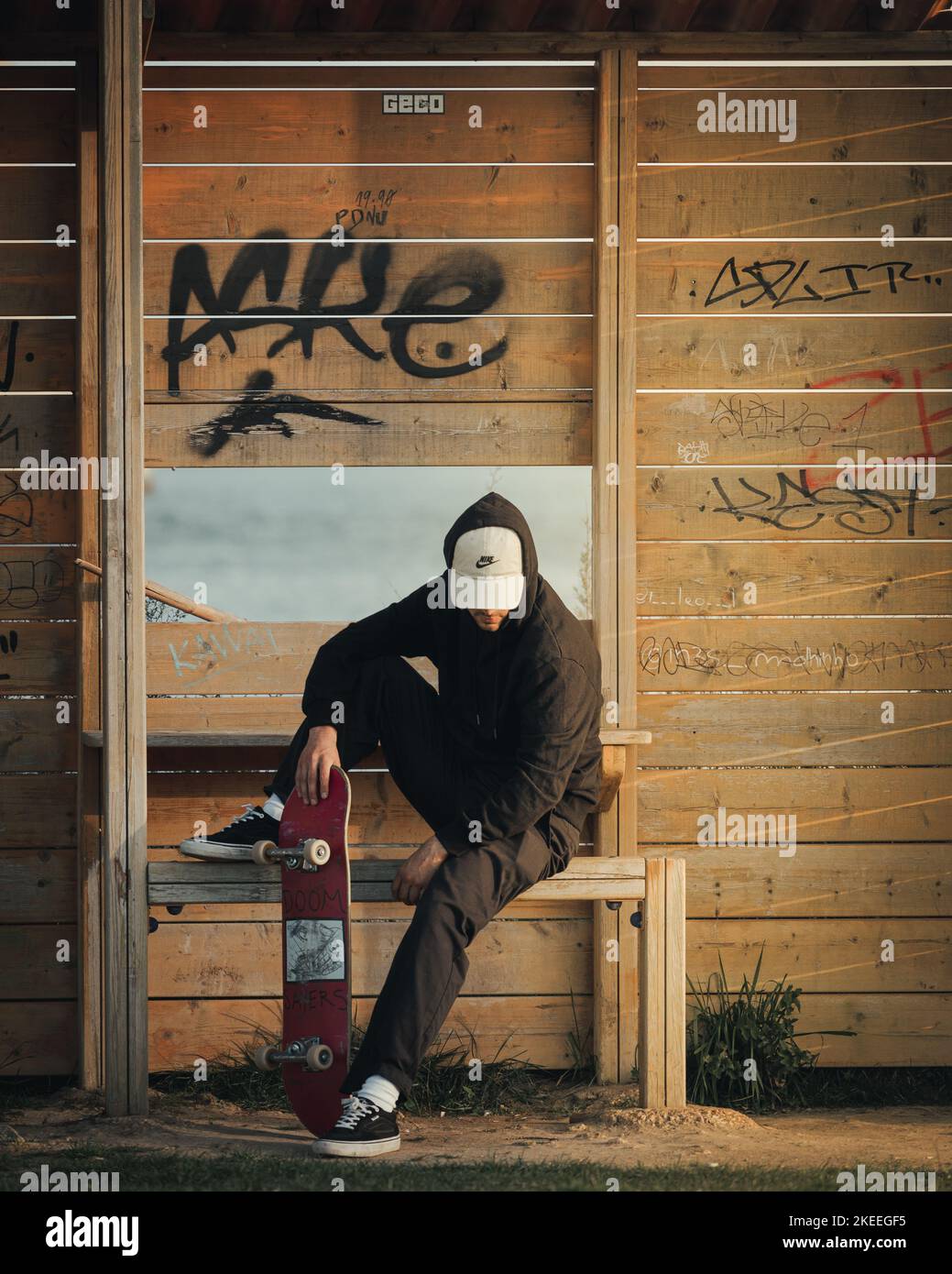A skater sitting on a bench in front of the wooden wall in graffiti ...