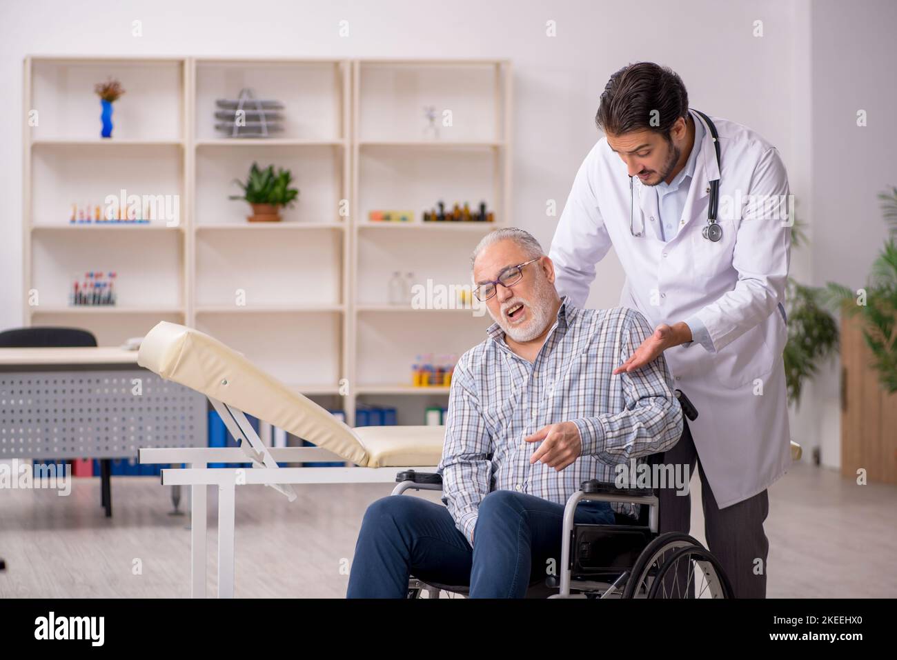 Old male patient in wheelchair visiting young male doctor Stock Photo ...