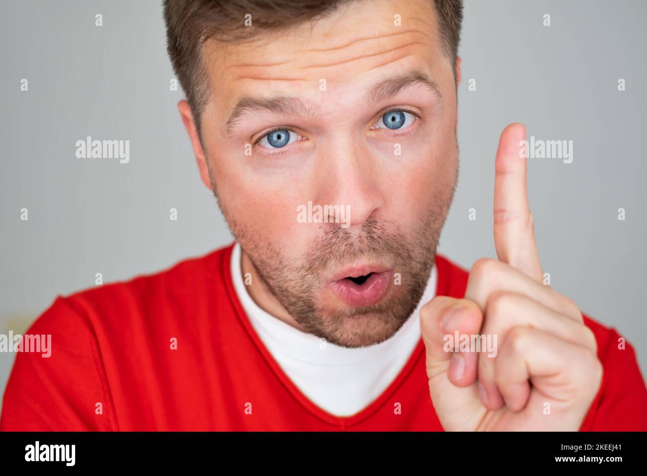 Satisfied young man showing index finger up, giving advice or ...