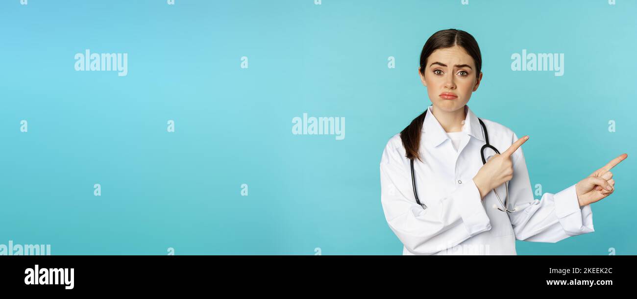 Portrait of disappointed doctor, woman medical worker pointing fingers ...