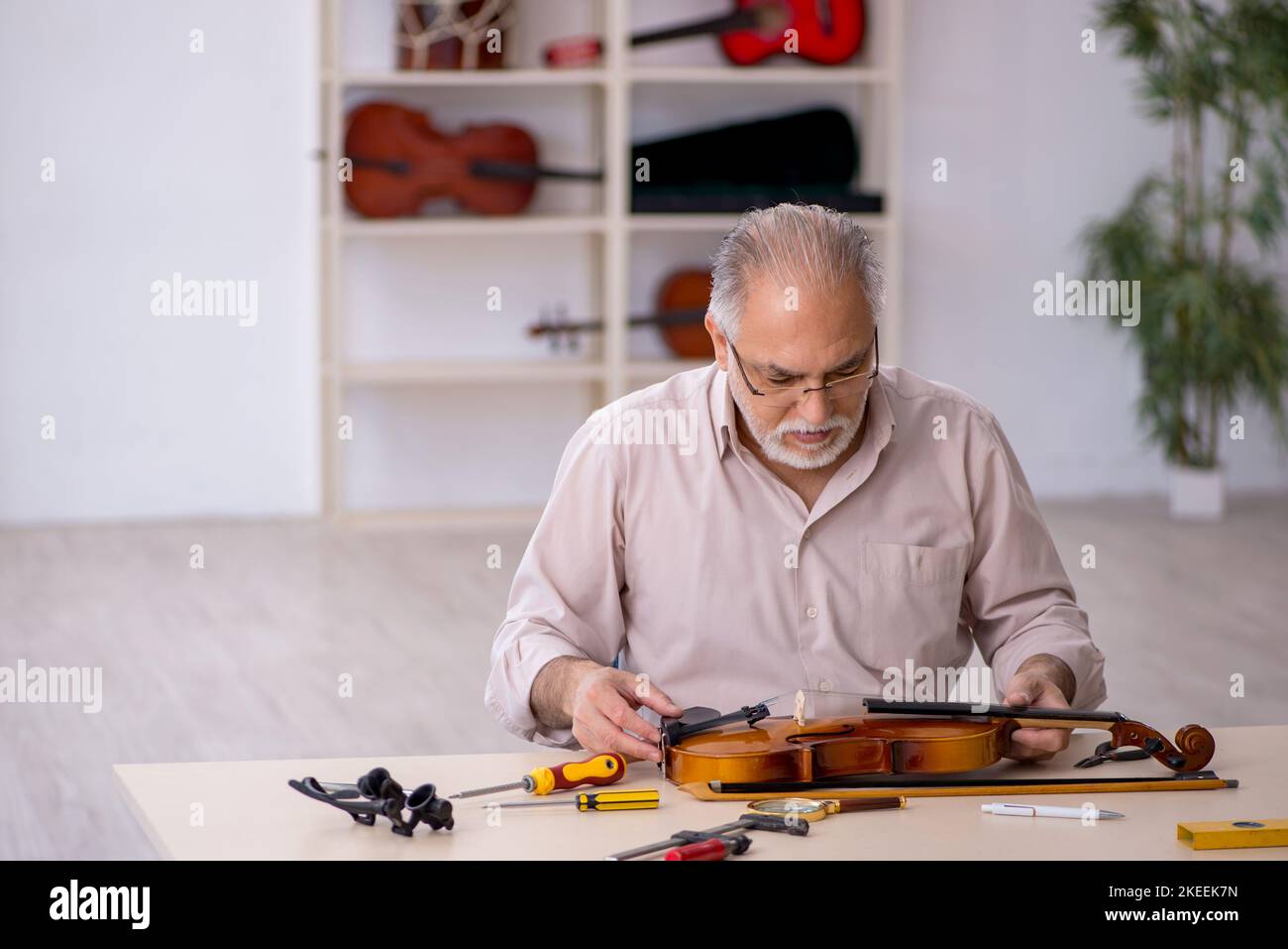 Old repairman repairing musical instruments at workshop Stock Photo - Alamy