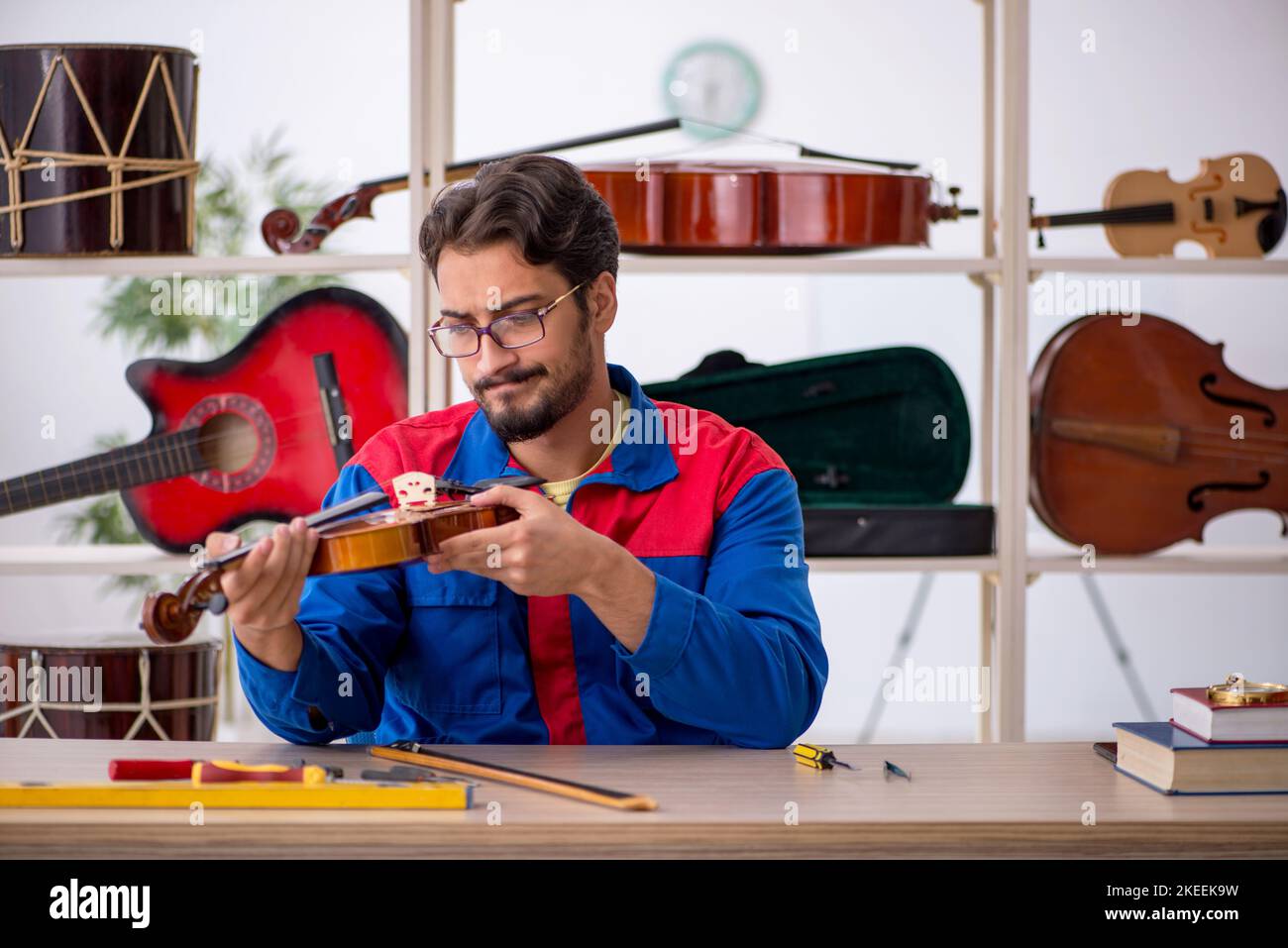 Young man repairing musical instruments indoors Stock Photo - Alamy
