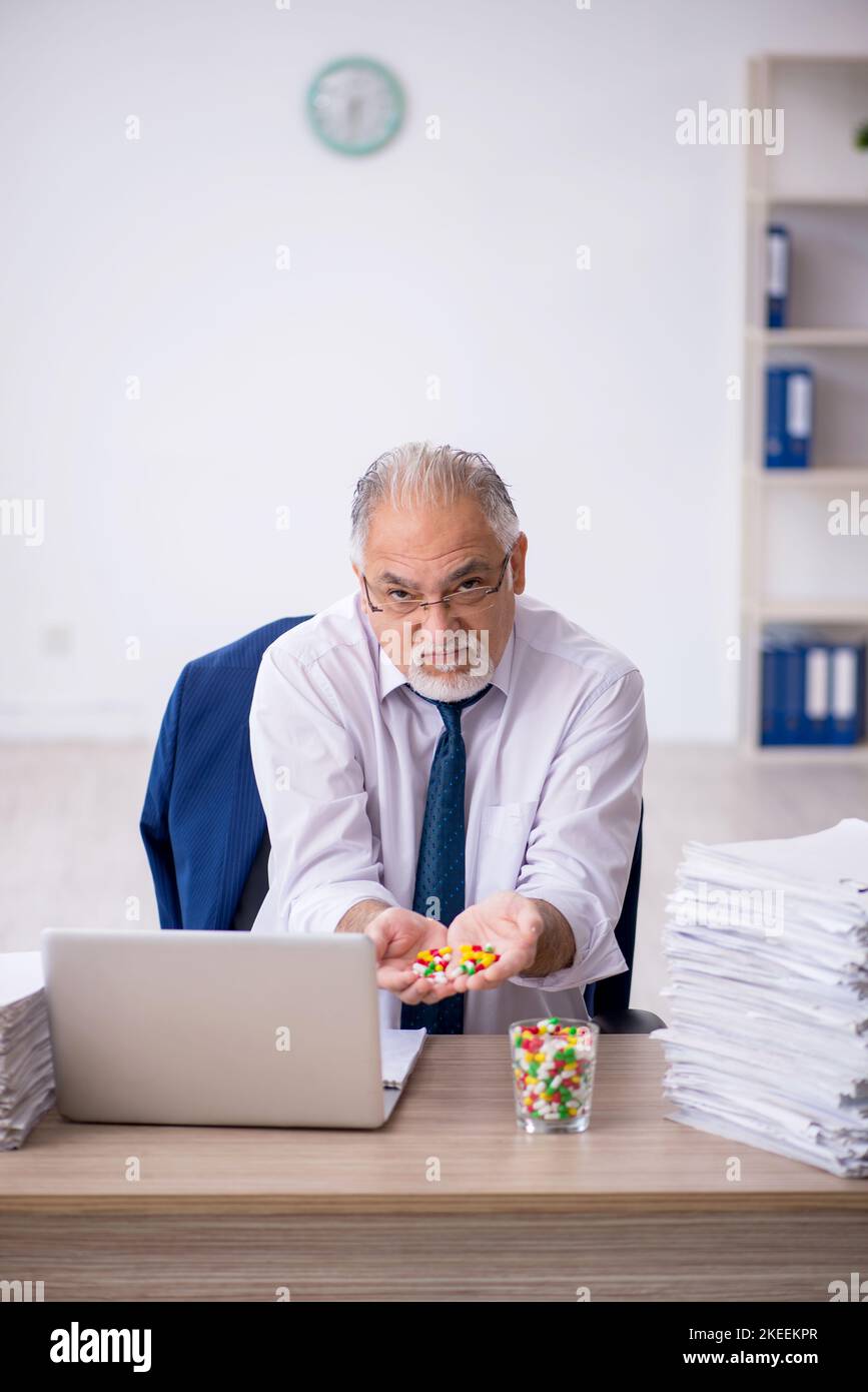 Old businessman employee suffering at workplace Stock Photo - Alamy
