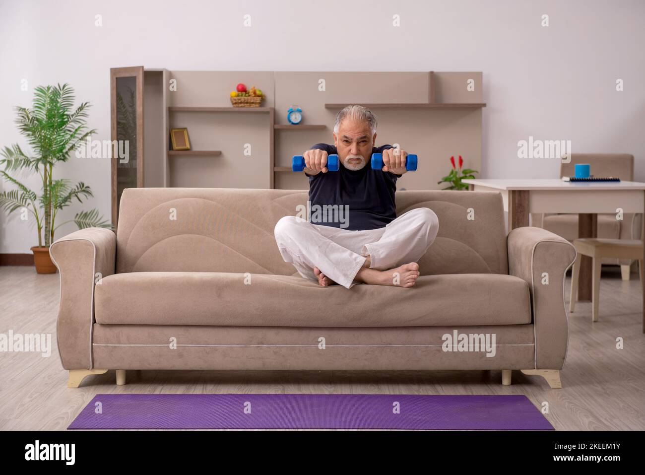Old man doing sport exercises indoors Stock Photo - Alamy