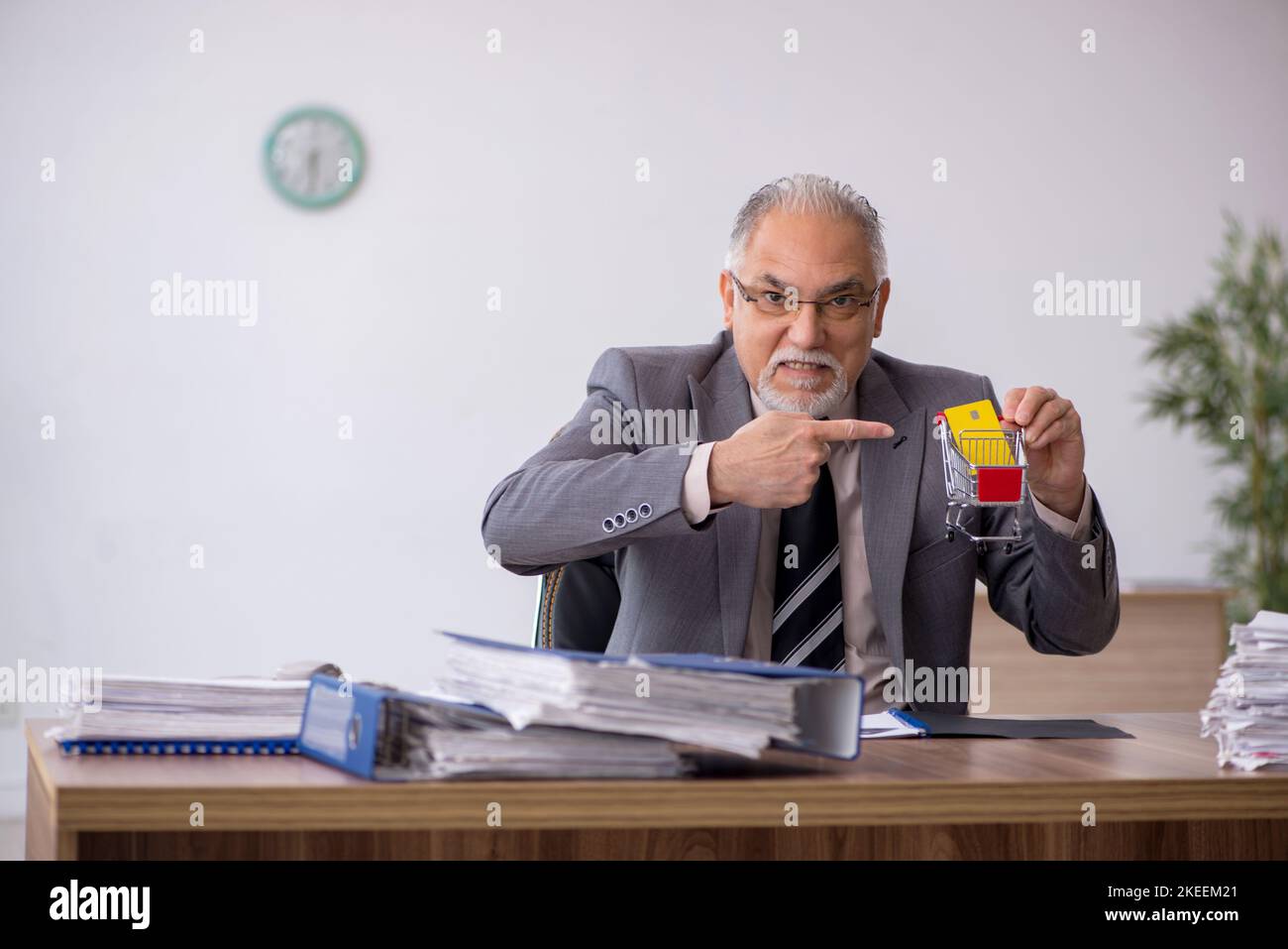 Old male boss holding credit card at workplace Stock Photo - Alamy