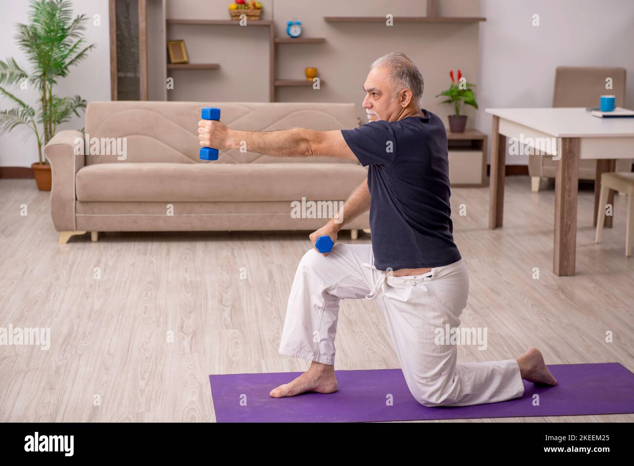 Old man doing sport exercises indoors Stock Photo - Alamy