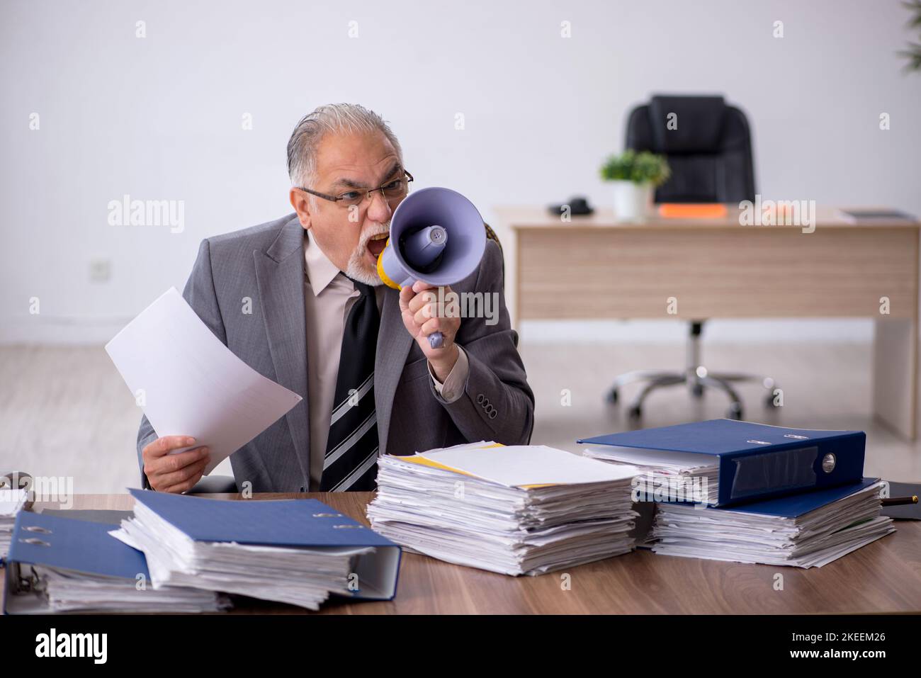 Old male boss holding megaphone at workplace Stock Photo - Alamy