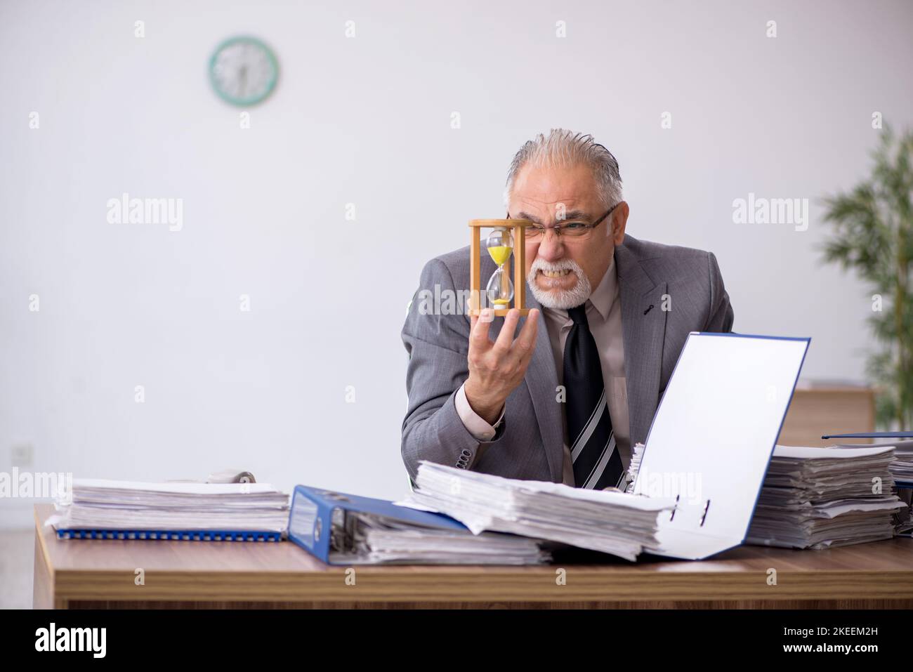 Old male boss in time management concept Stock Photo - Alamy