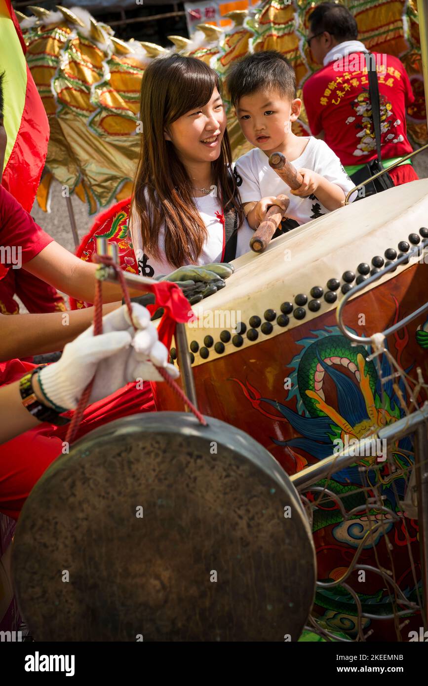 A villager lets her young son beat the ceremonial drum for the dragon ...