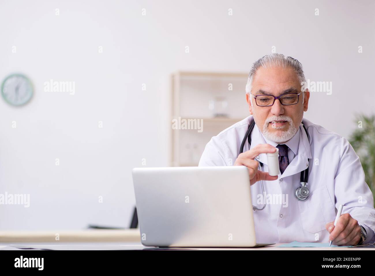 Old male doctor working in the clinic Stock Photo - Alamy