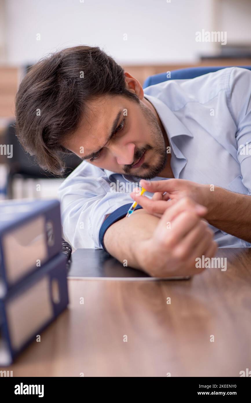 Young male drug addicted employee in the office Stock Photo - Alamy