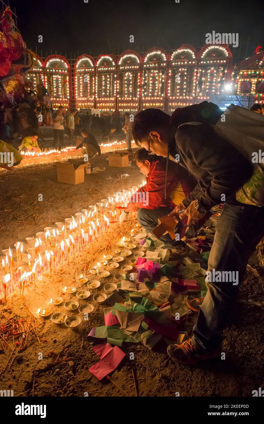 A villager adds joss paper to the other offerings at night at the ...