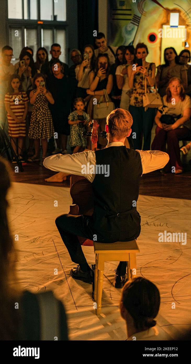 A vertical of a Caucasian musician seen from behind, playing a melody ...